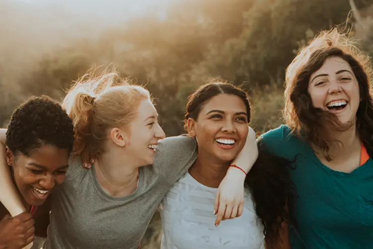 4 women sat laughing together